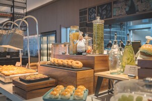 Buffet com diversos alimentos, incluindo pães e doces.