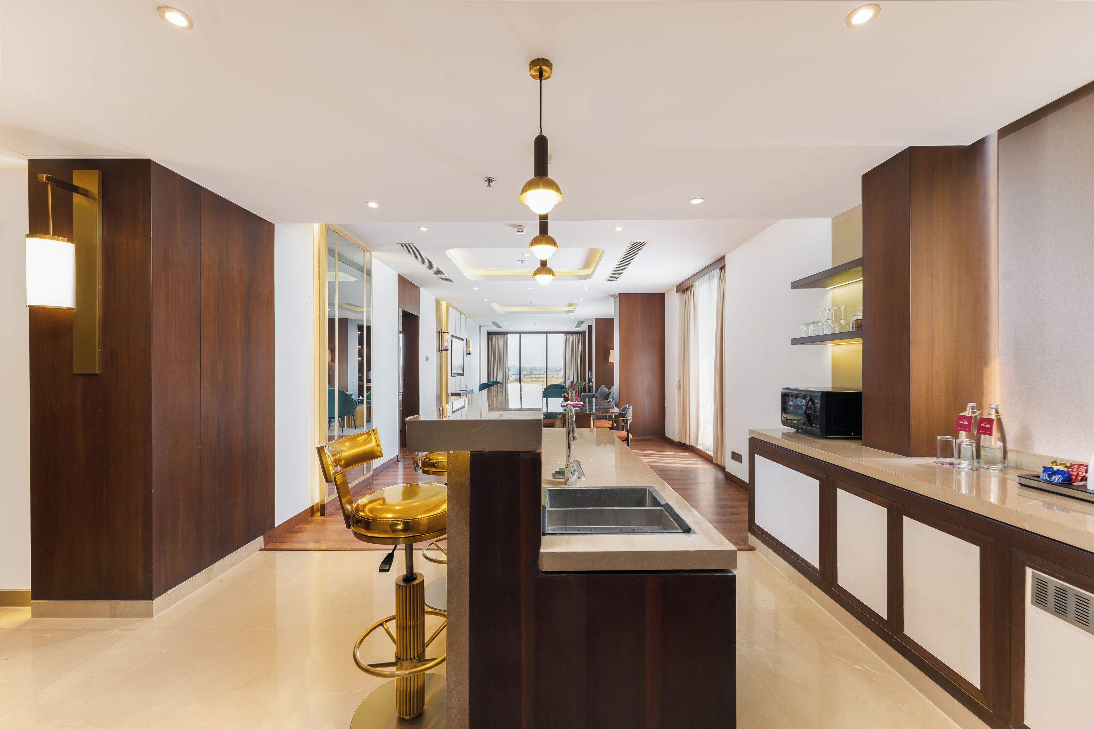 Um hall de hotel moderno com uma recepção central, área de bar e um espaço de estar com uma cadeira dourada.