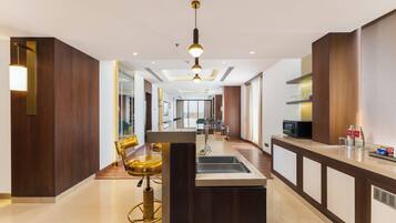 Um hall de hotel moderno com uma recepção central, área de bar e um espaço de estar com uma cadeira dourada.