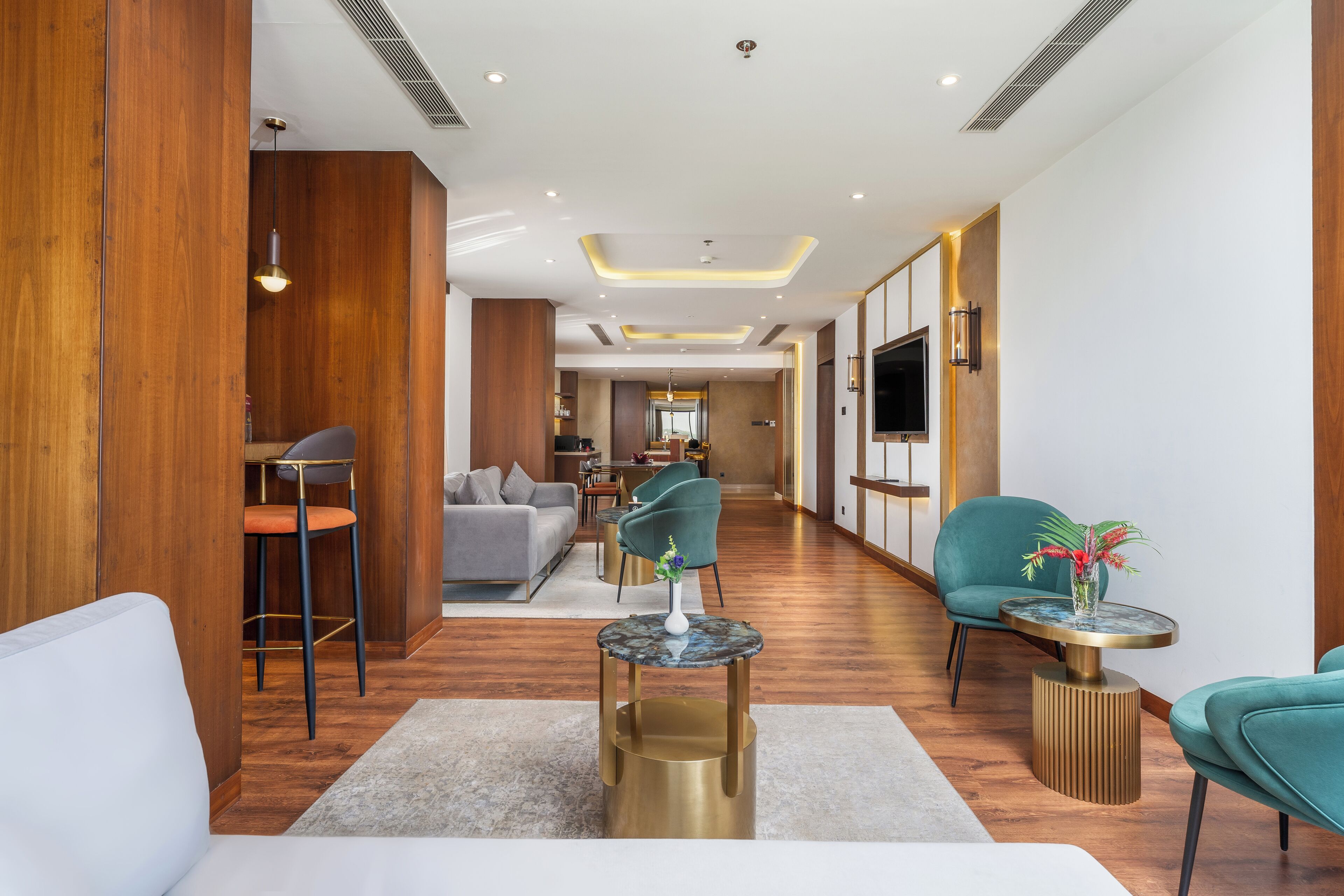 Um lobby de hotel moderno com um sofá, cadeiras, uma televisão e uma parede de destaque em madeira.