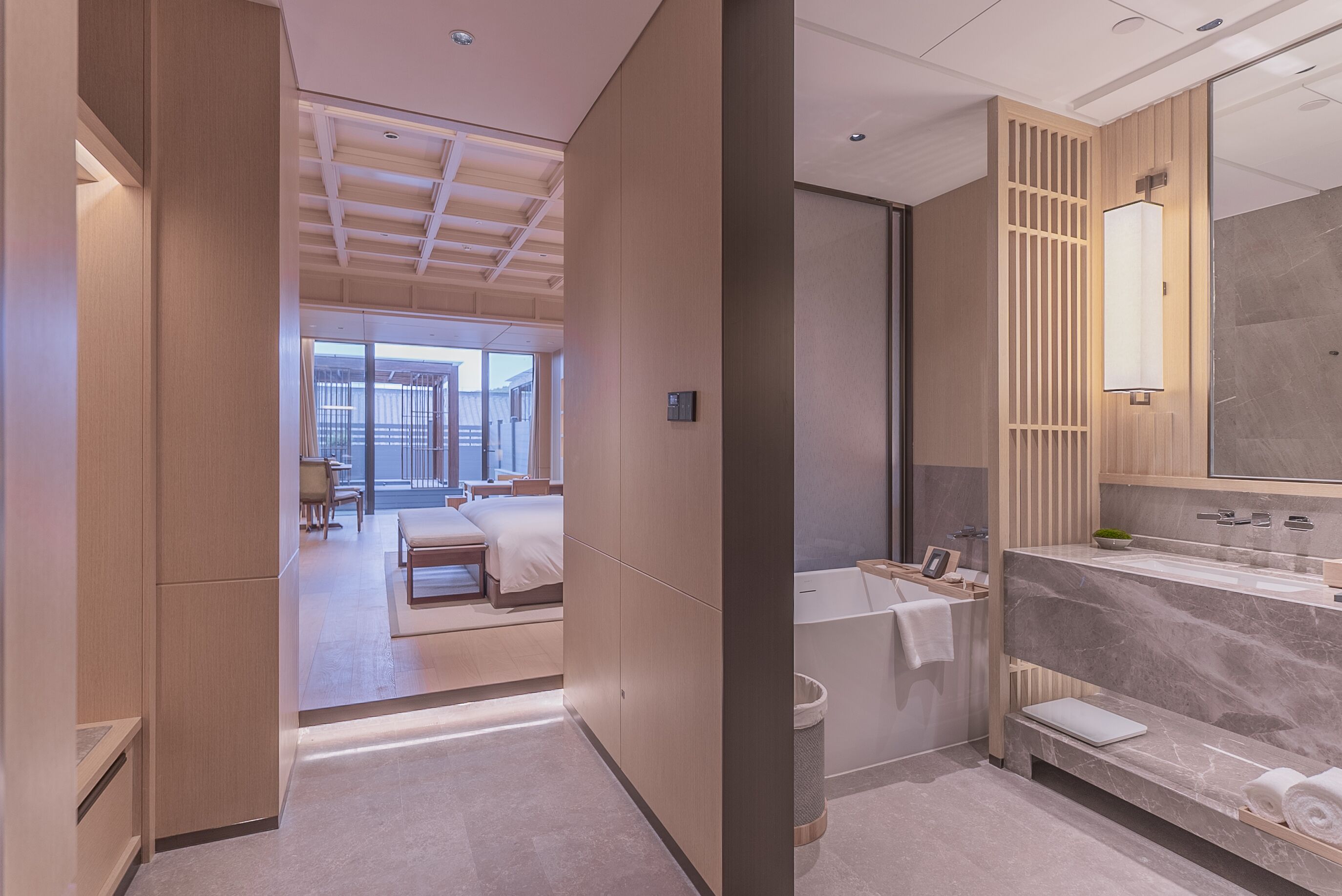 Quarto de hotel moderno com uma cama grande, banheiro com banheira e vista para a cidade.