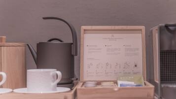 Máquina de café com manual, uma chávena e um tabuleiro com cápsulas de café.