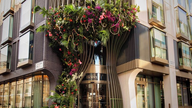 Um edifício moderno com entrada curva, janelas amplas e uma placa com a inscrição 'Boulée'.