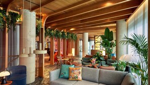 Um hall com teto de madeira, áreas de estar e plantas internas.