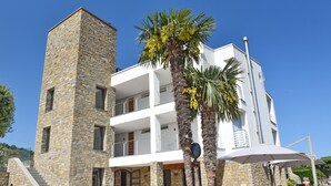 Um edifício moderno de dois andares com fachada de pedra, varandas e área de estar ao ar livre.