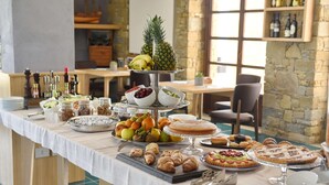 Mesa de buffet com diversos alimentos e uma estante de vinhos ao fundo.