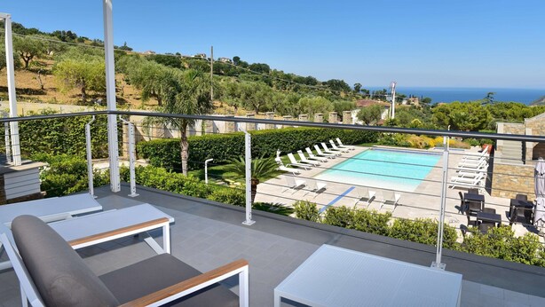 Terraço no telhado com piscina, espreguiçadeiras e vista para o mar.