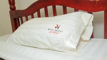 Uma cama com travesseiro exibindo o logotipo da Richy Hotels and Safari.