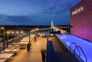 Área de piscina no terraço com espreguiçadeiras e vista para uma ponte.