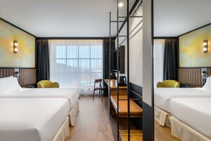 Quarto de hotel com duas camas, uma escrivaninha, uma cadeira e uma escada.