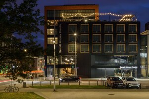 Um edifício moderno com fachada de vidro e uma placa com a inscrição 'Barceló Warsaw Powiśle'.