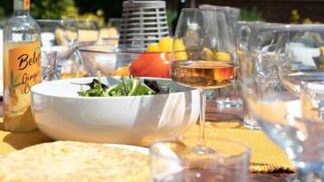 Mesa posta ao ar livre com uma garrafa de Bena Ginger Ale, uma saladeira e um copo de vinho.