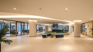 Um hall amplo com teto curvo, grande área de estar e vista para o exterior através de portas de vidro.