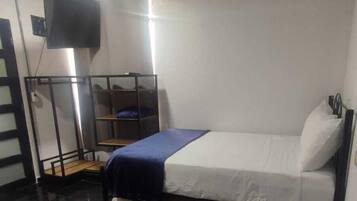 Quarto pequeno e moderno com cama, televisão na parede e escada.