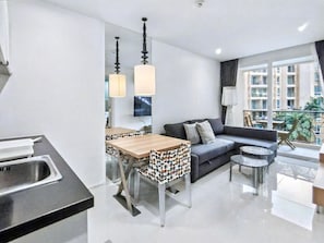 Uma sala de estar moderna com um sofá, uma mesa de jantar e uma área de cozinha com uma pia e uma mesa redonda pequena.