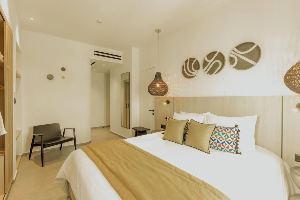 Quarto de hotel moderno com uma cama grande, uma cadeira e um espelho.