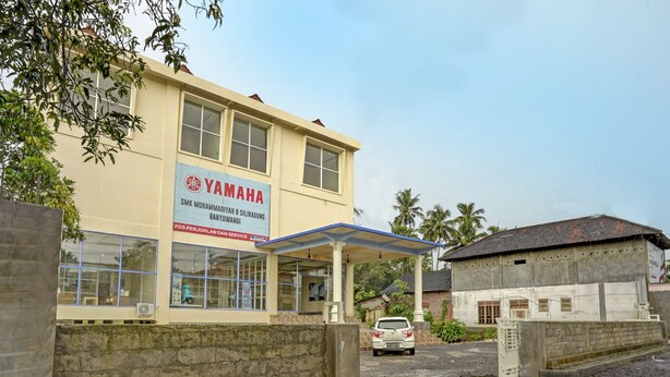 Um edifício com a placa Yamaha, entrada coberta e um carro estacionado na frente.