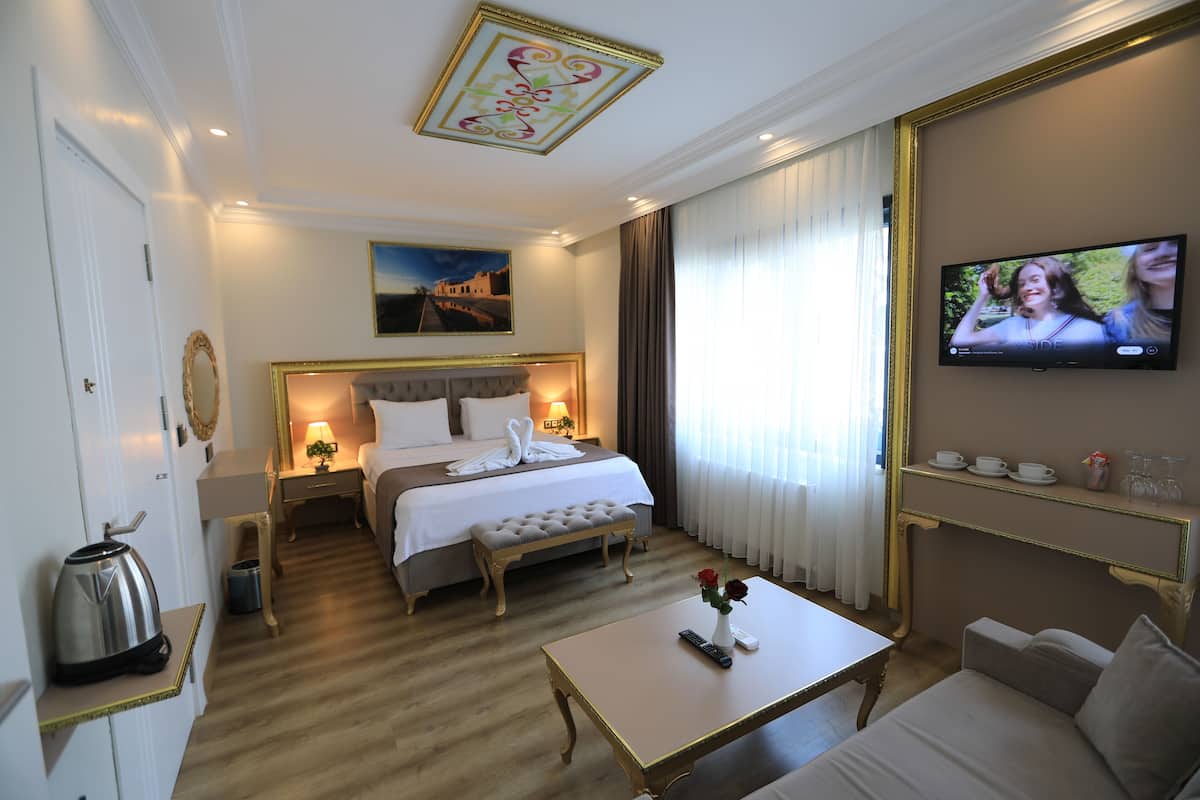 Quarto de hotel com cama, televisão, mesa de centro e sofá.