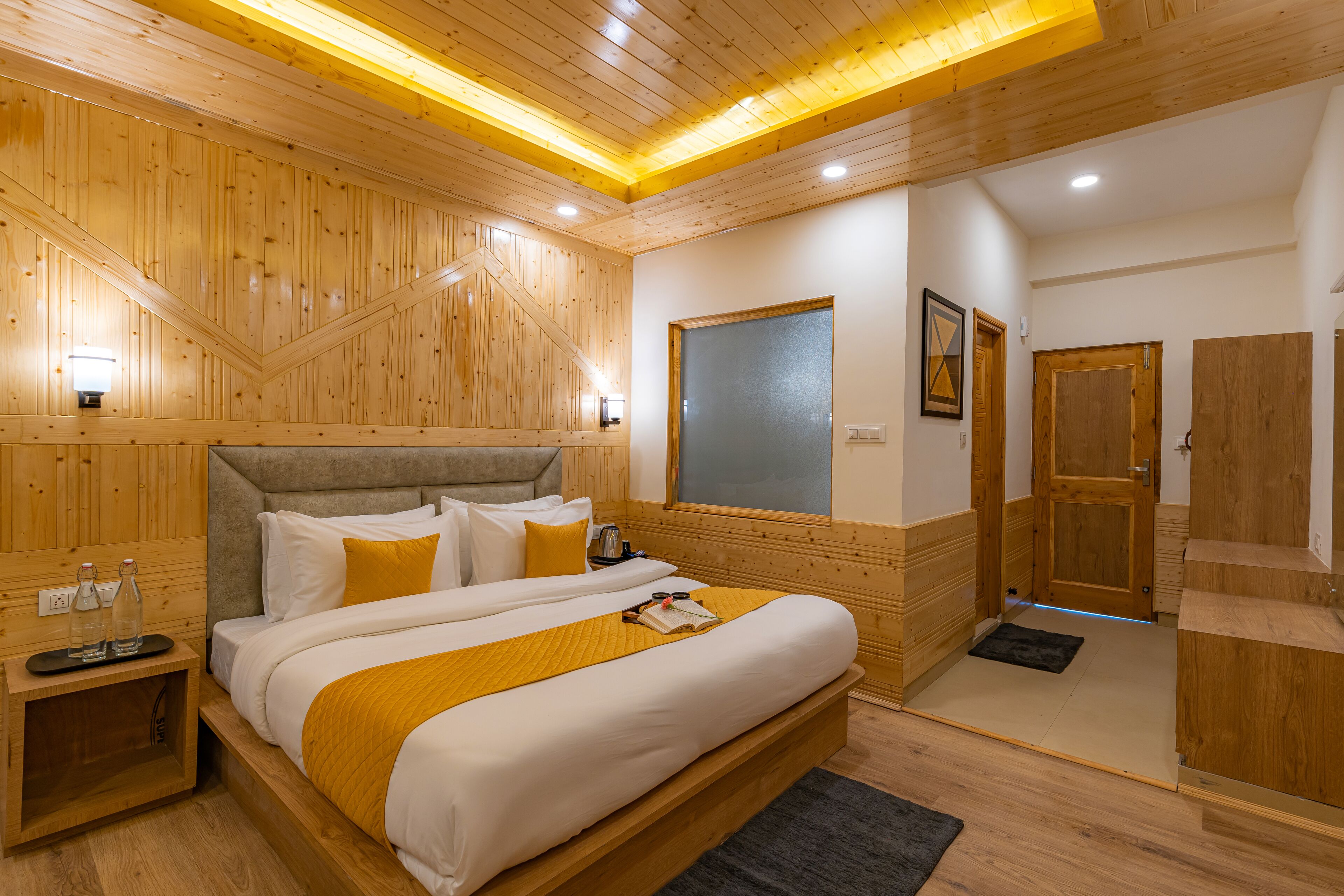 Um quarto com painéis de madeira, uma cama, mesas de cabeceira e uma janela grande.