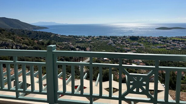 Uma vila costeira com vista para o mar e colinas ao fundo.