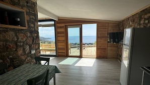 Uma cozinha espaçosa com mesa e cadeiras de madeira, geladeira e parede de pedra.