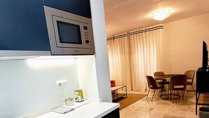 Uma cozinha moderna com armários escuros, micro-ondas embutido e bancada branca.
