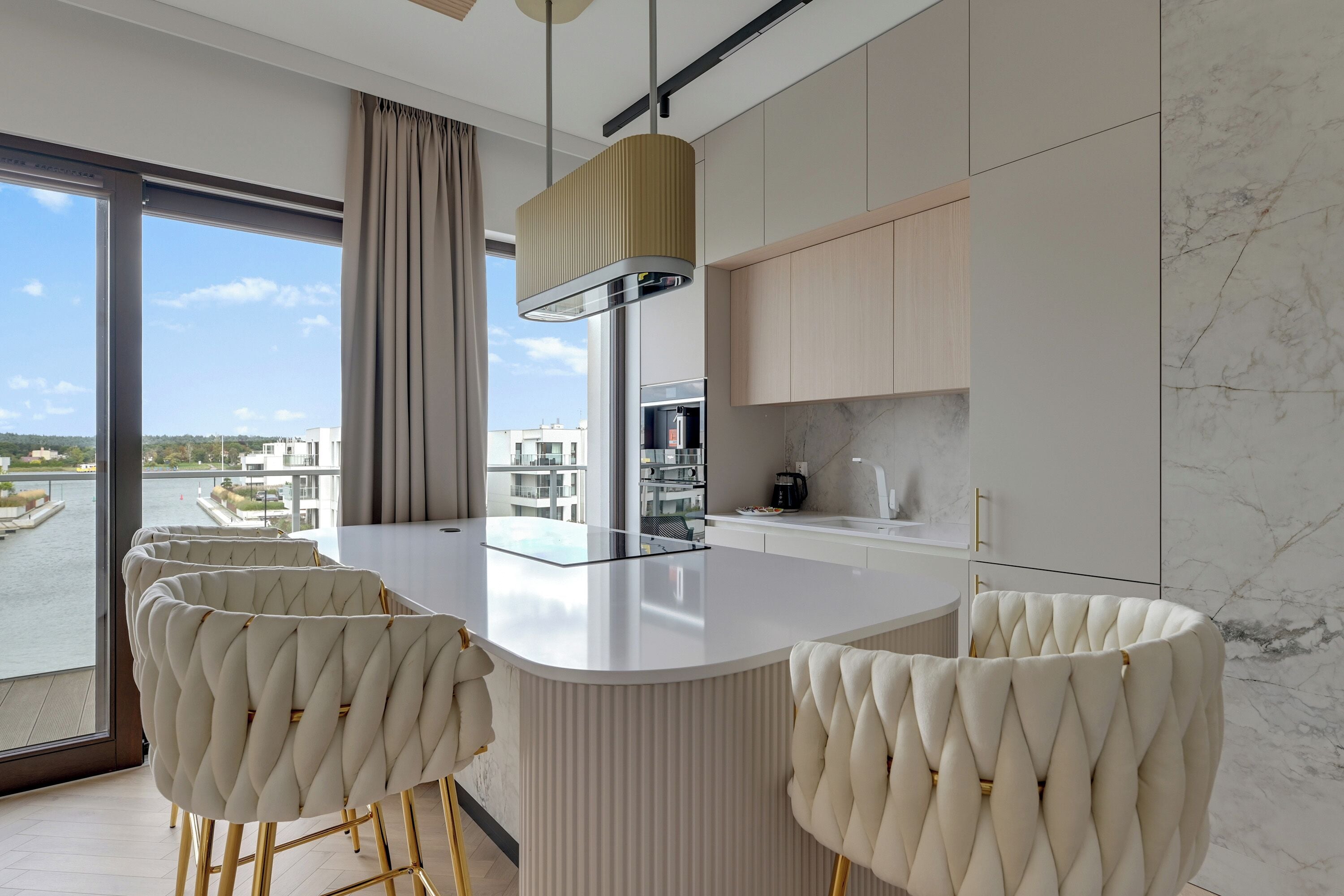Cozinha moderna com ilha central, banquetas e vista para a água.