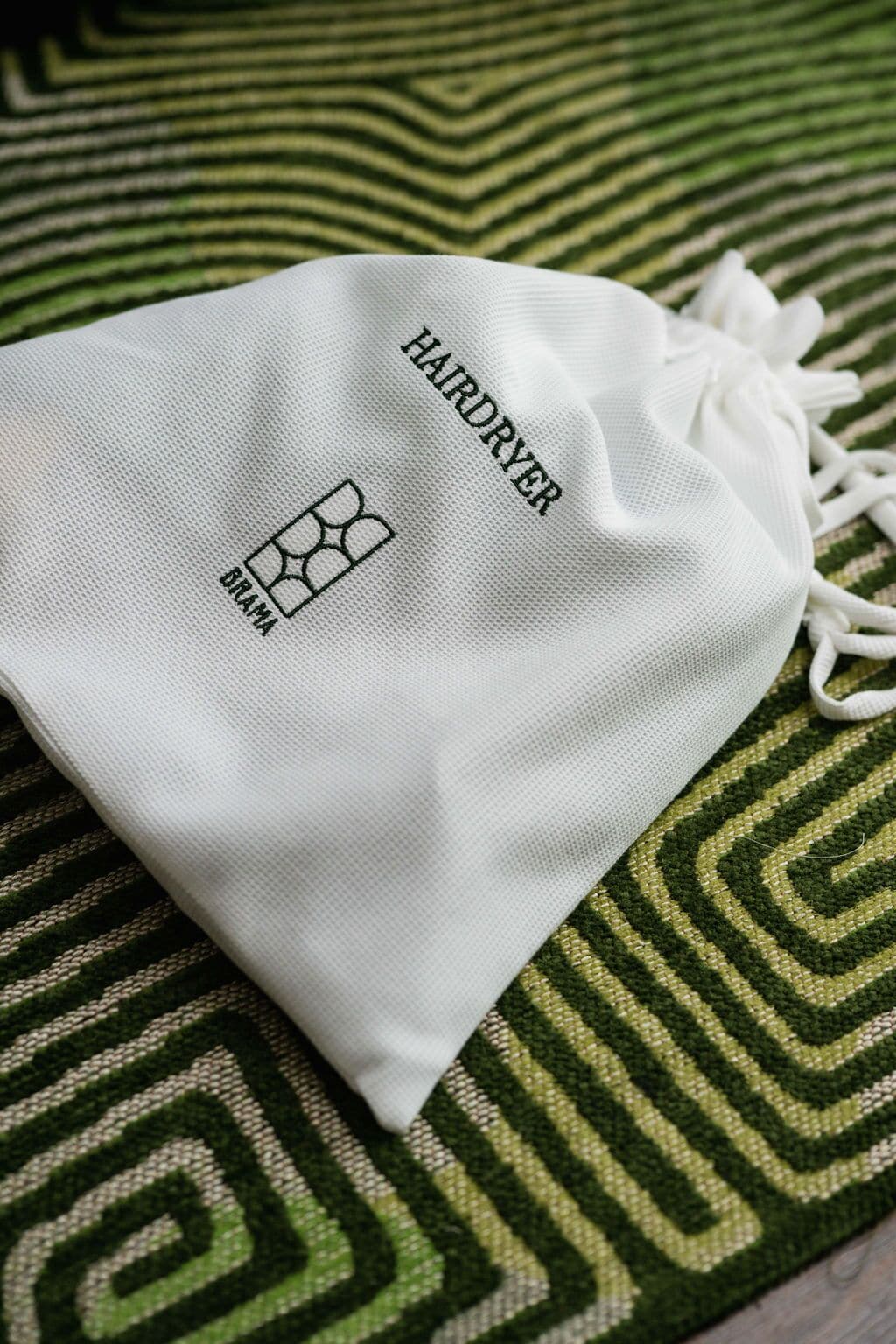 Uma sacola branca com cordão e a inscrição 'HAIRDRYER' e 'BRAMA'.