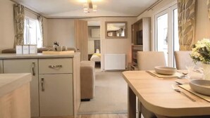 Quarto compacto e bem iluminado, com cozinha compacta, área de refeições e uma cama.