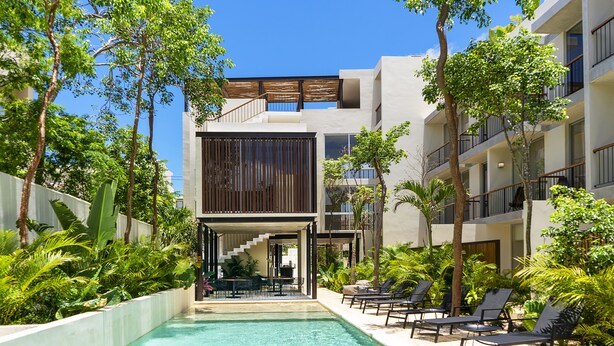Hotel moderno com piscina, área de estar externa e vegetação exuberante.