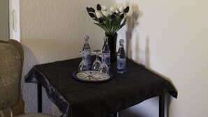 Quarto nos cantos com um relógio, quadro emoldurado e uma mesa com um vaso e garrafas.