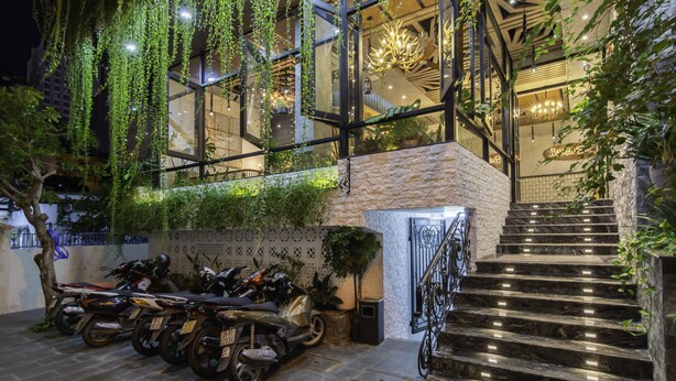 Um edifício com plantas pendentes, uma escadaria e motocicletas estacionadas.