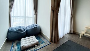 Um quarto com uma cama, uma mesinha e uma janela com cortinas.