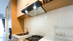 Uma cozinha moderna com pia de aço inoxidável, fogão embutido e backsplash de azulejos brancos.