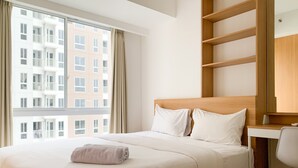 Quarto de hotel com uma cama grande, uma escrivaninha e vista para um edifício pela janela.