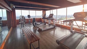 Uma academia com esteiras, um banco e aparelhos de musculação.
