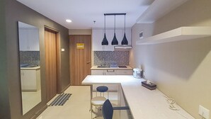 Cozinha compacta com área de refeições, um espelho grande e uma luminária pendente moderna.
