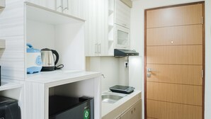 Uma cozinha compacta com armários brancos, micro-ondas, chaleira, balança e máquina de café preta.