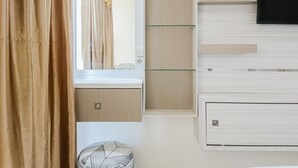 Quarto de hotel moderno com um armário de madeira, uma pequena planta em vaso e uma televisão montada.