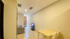 Uma sala de estar moderna com sofá, televisão em um móvel e mesa de jantar com cadeiras.