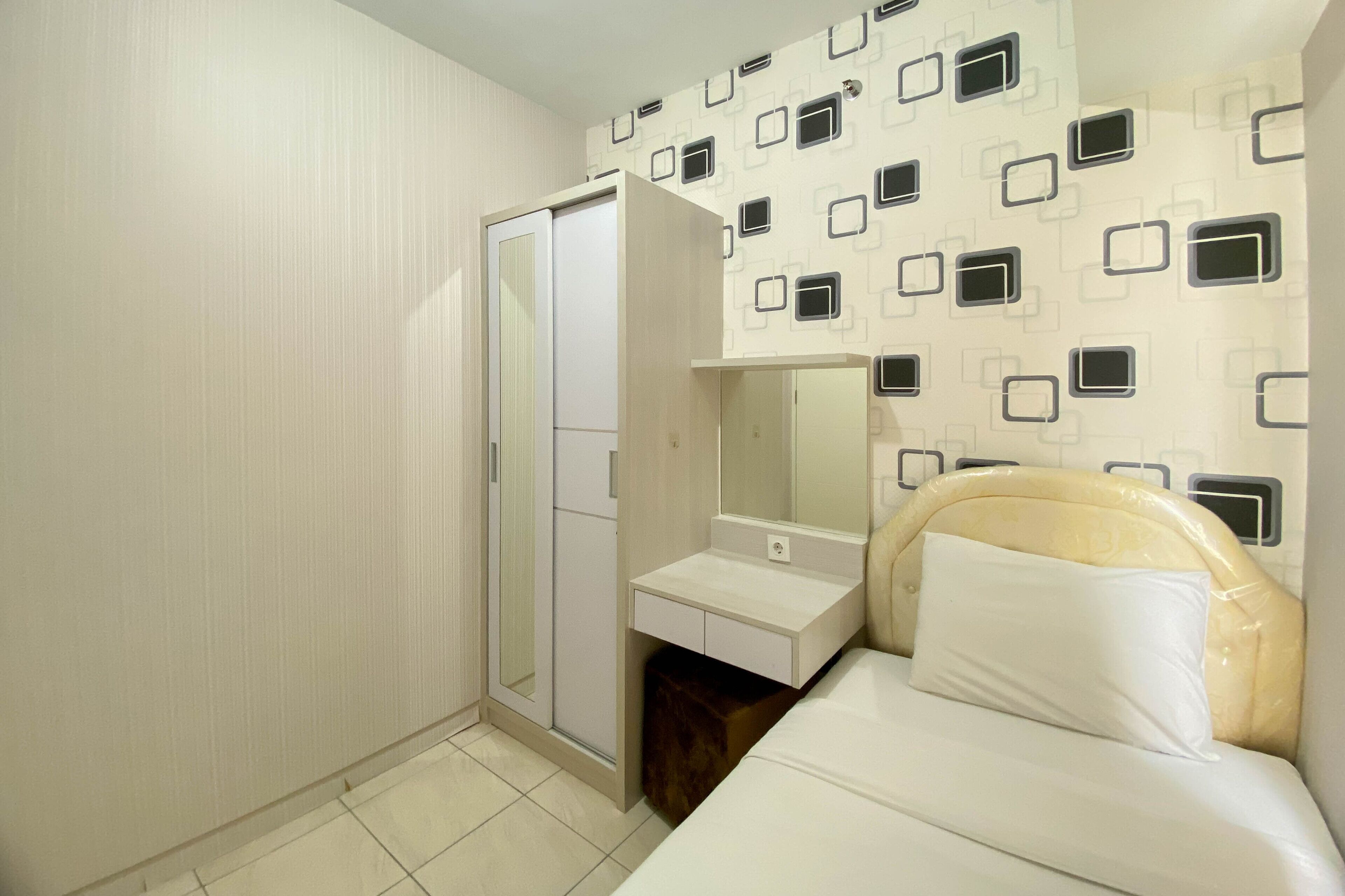 Quarto com cama, mesa de cabeceira, espelho e guarda-roupa.