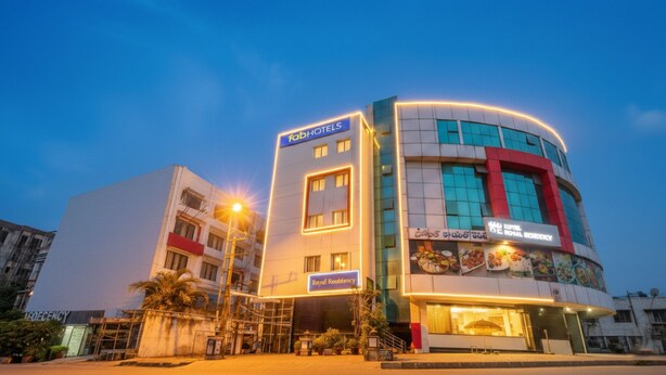 Um hotel com design moderno, exibindo um letreiro 'FOBHOTELS', um restaurante 'Royal Bengal' e uma placa 'Rental Real Estate'.