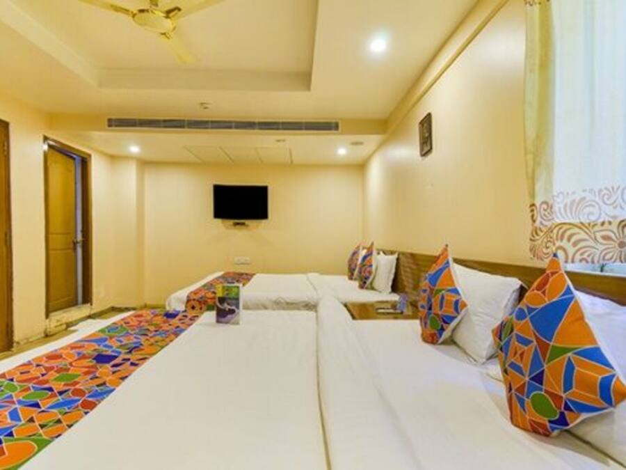 Quarto de hotel com duas camas, uma televisão na parede e um travesseiro decorativo.