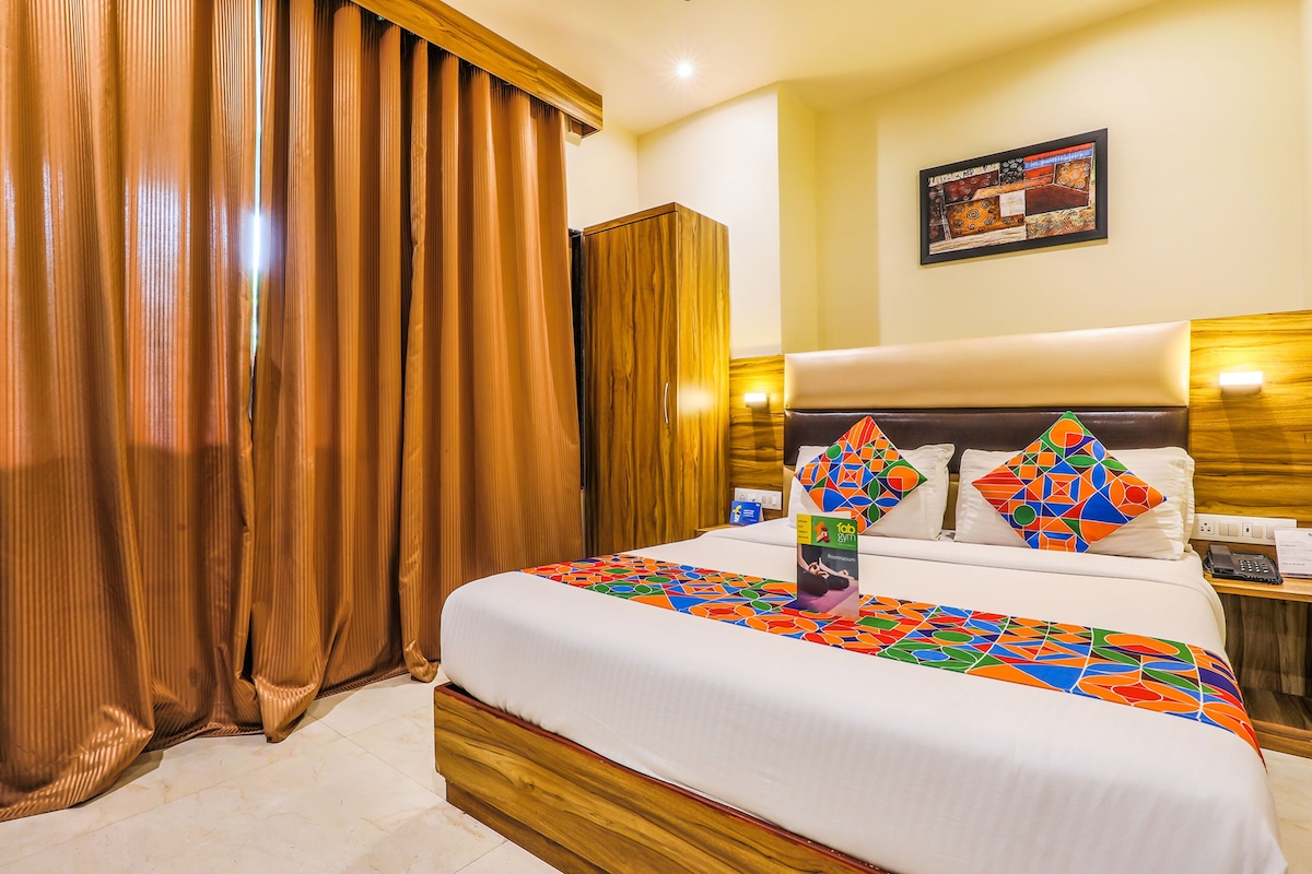 Quarto de hotel com uma cama grande, um guarda-roupa de madeira e um quadro na parede.