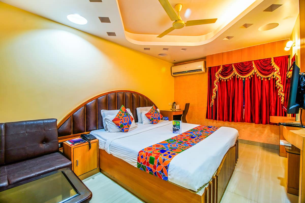 Quarto de hotel com cama, sofá, escrivaninha e ar condicionado.