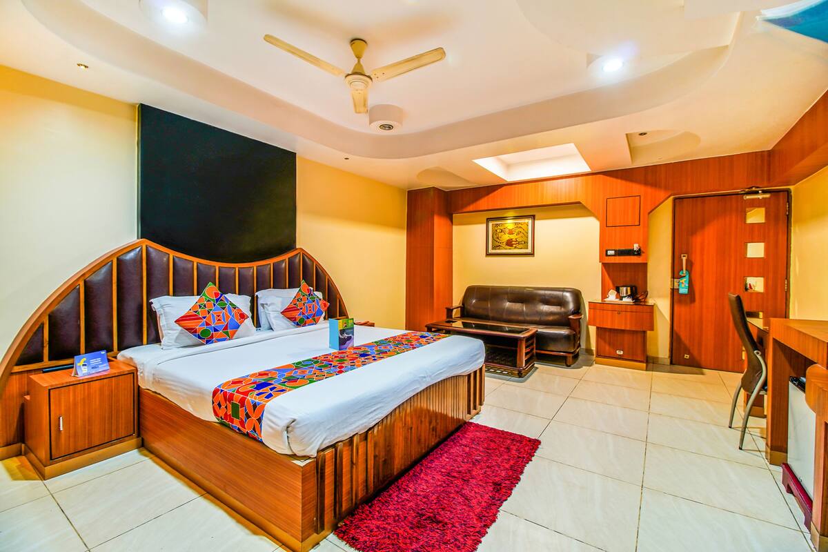 Quarto com cama de madeira, tapete vermelho, escrivaninha e cadeira.