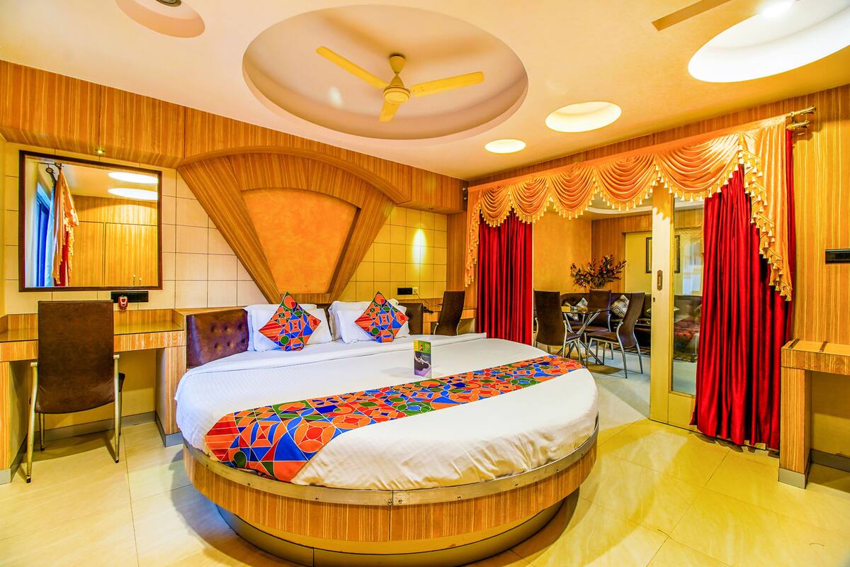 Quarto de hotel com uma cama grande, uma mesa de trabalho, uma cadeira e um espaço de refeições com mesa e cadeiras.