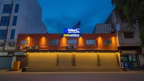 Um edifício com uma placa indicando 'Fab Hotels' e uma porta com persiana fechada.