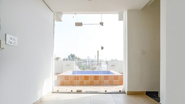Um quarto com uma janela grande, piso de azulejos e vista para edifícios.