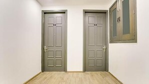 Duas portas fechadas em um corredor com piso de madeira.